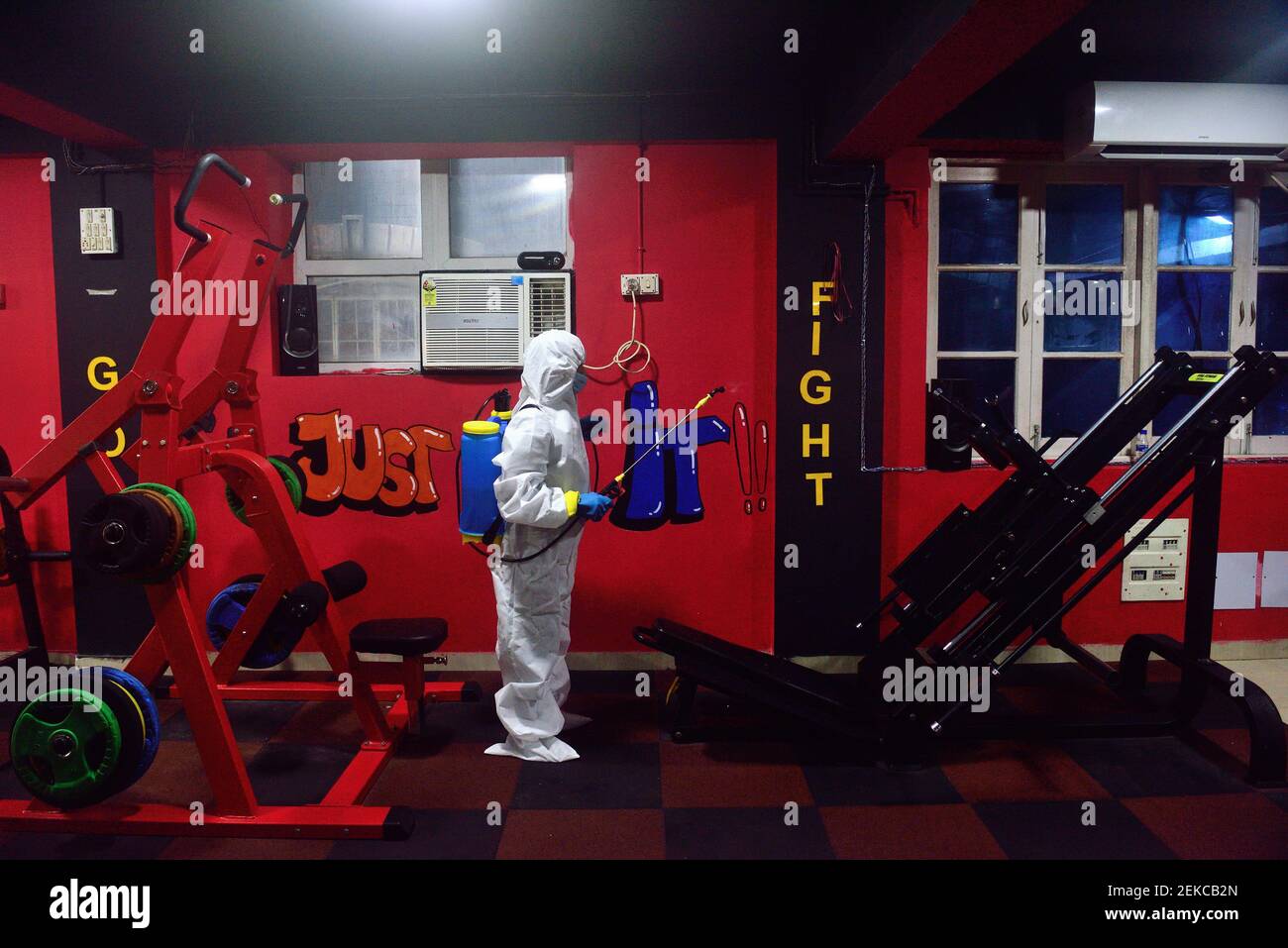 A worker wearing a personal protective equipment suit (PPE) sanitizes ...