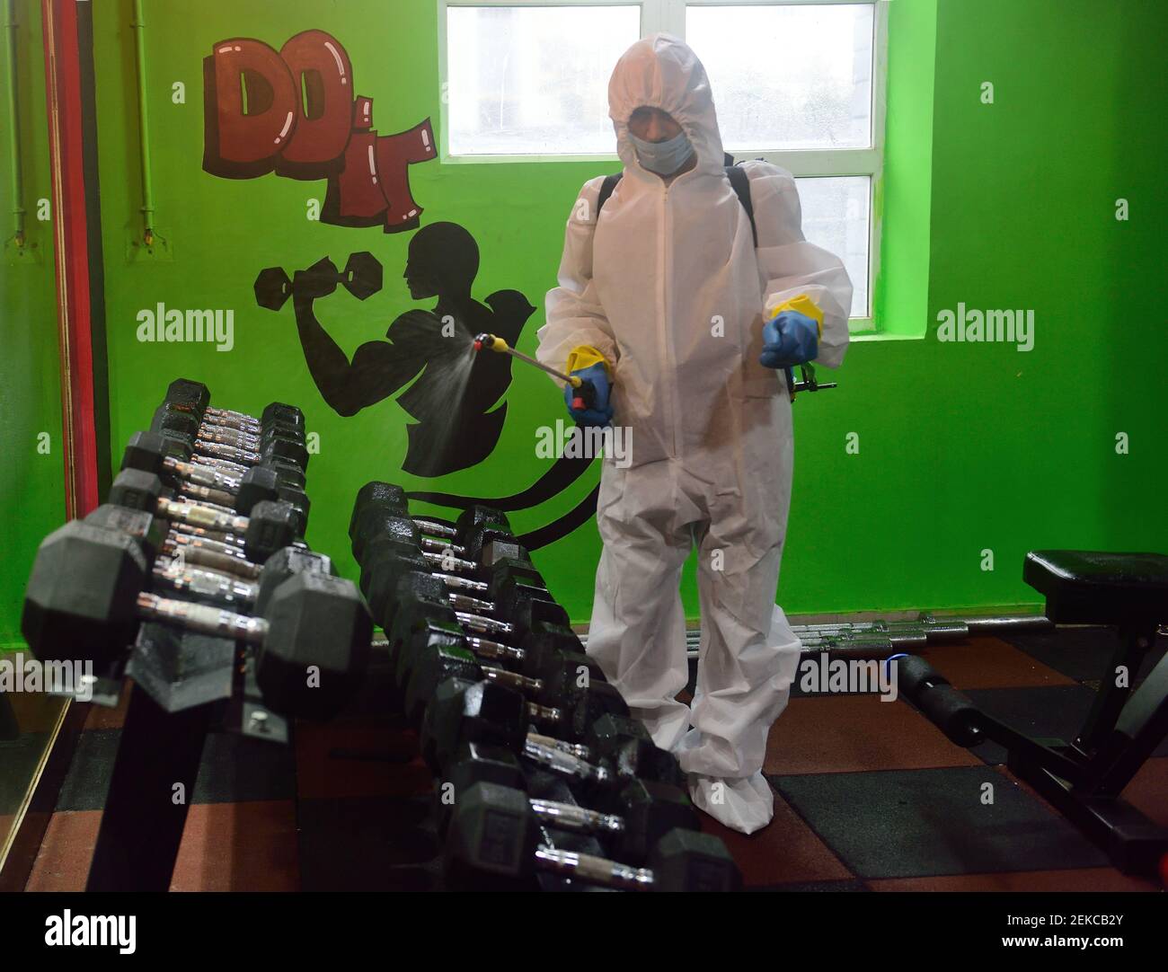 A worker wearing a personal protective equipment suit (PPE) sanitizes ...