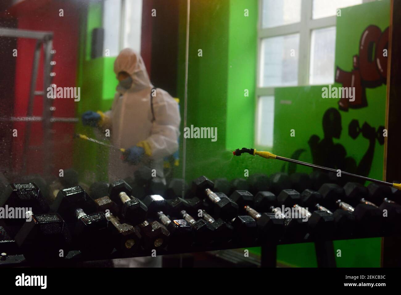 A worker wearing a personal protective equipment suit (PPE) sanitizes ...