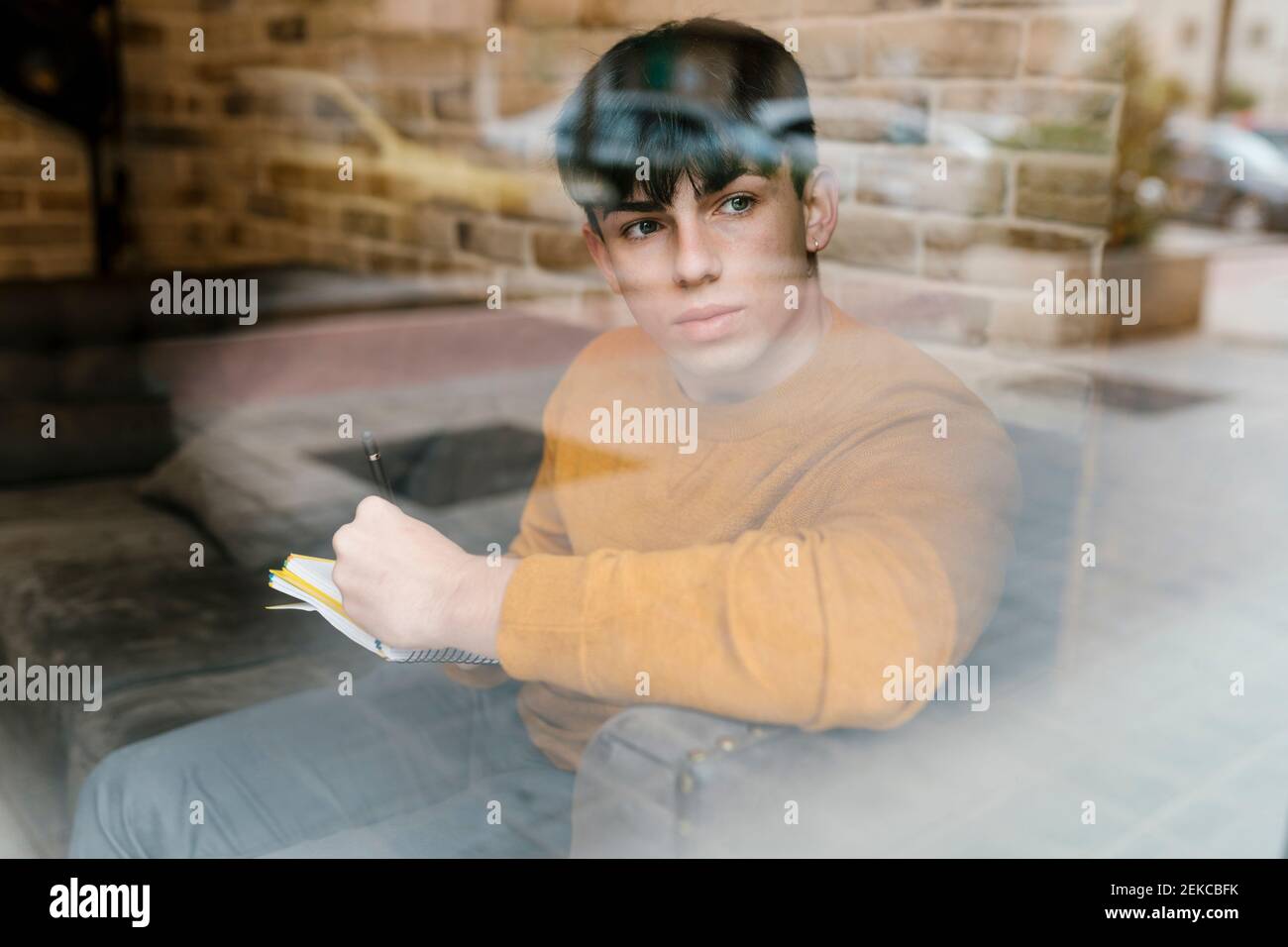 Man with book looking through window while sitting at cafe Stock Photo ...