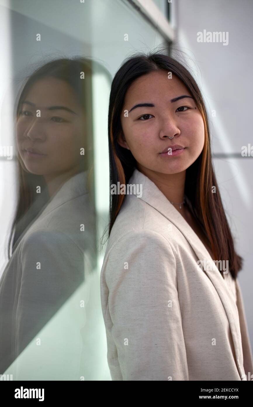 Beautiful woman standing against glass wall Stock Photo - Alamy