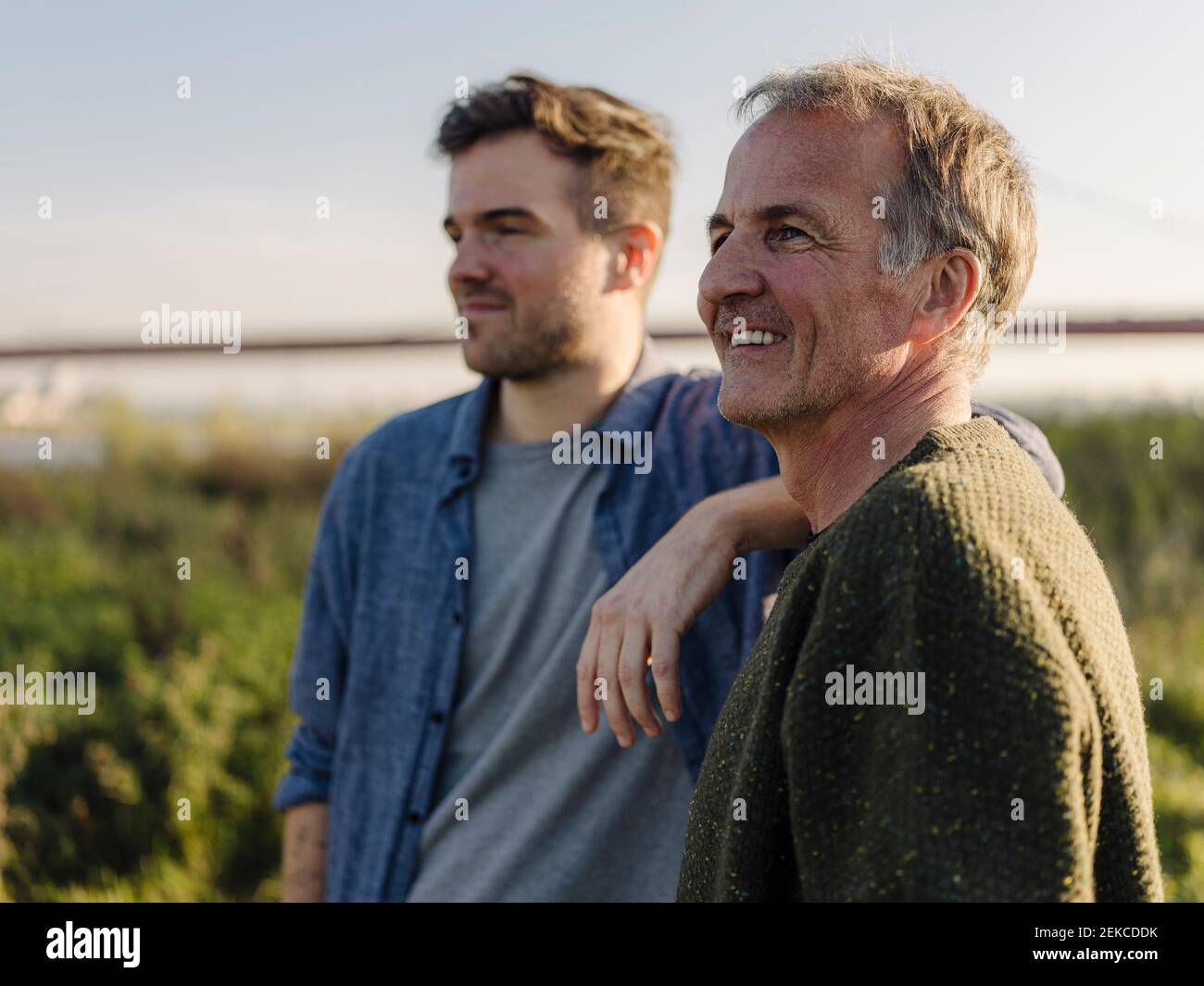 Thoughtful father and son looking at riverbank Stock Photo - Alamy