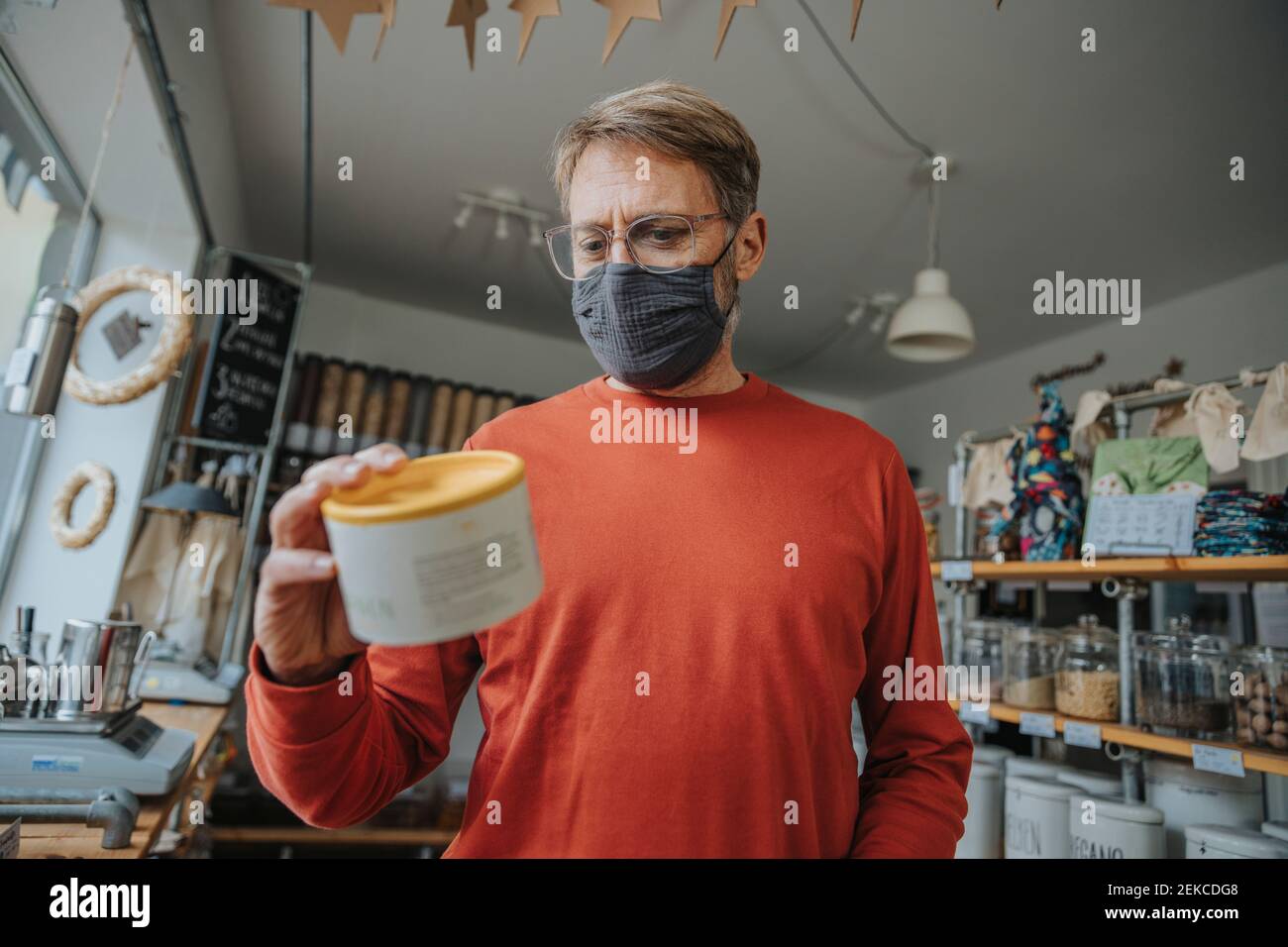 Mature man checking label on food container in zero waste shop during ...