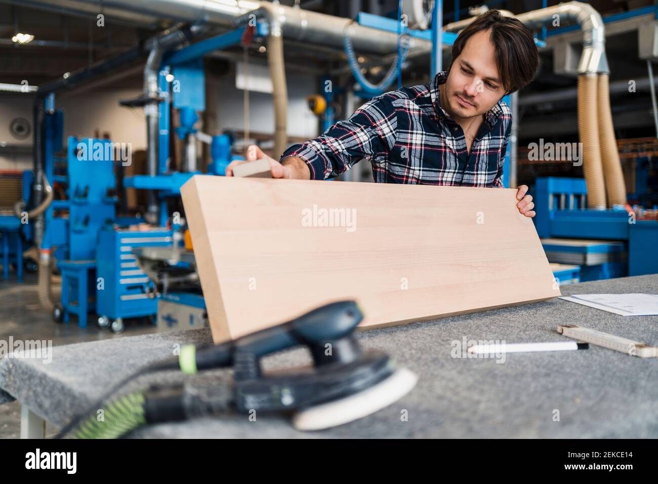 Industrial worker measuring wood plank while standing at industry Stock ...