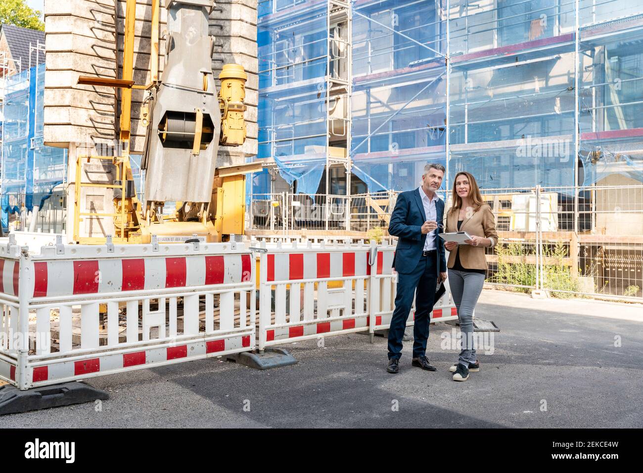 Businessman standing by colleague holding file while standing at ...