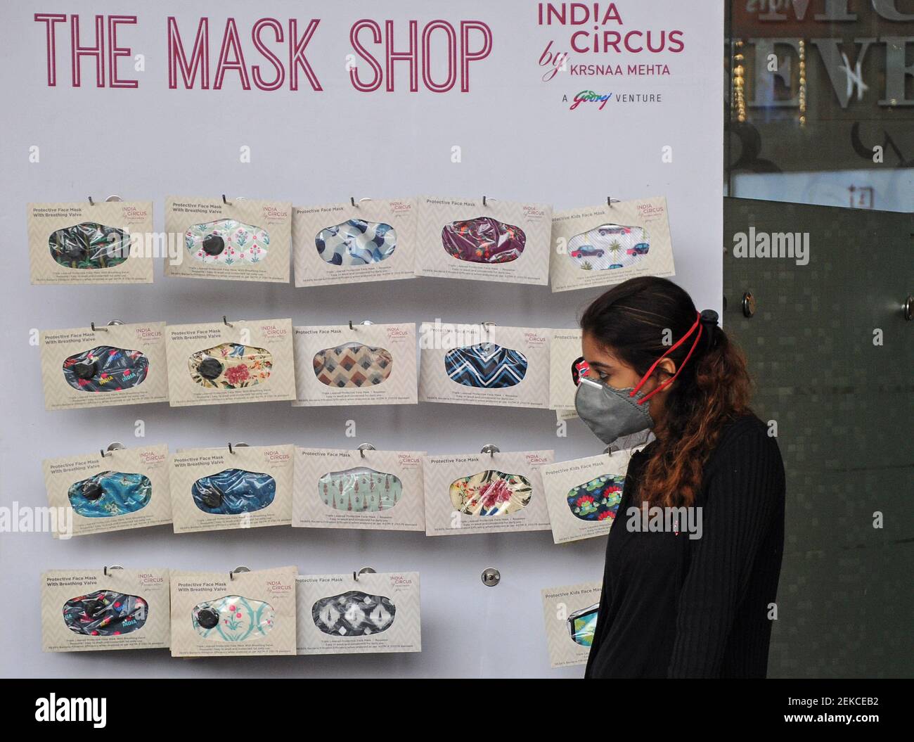A woman wearing a protective mask stands next to a store selling face ...