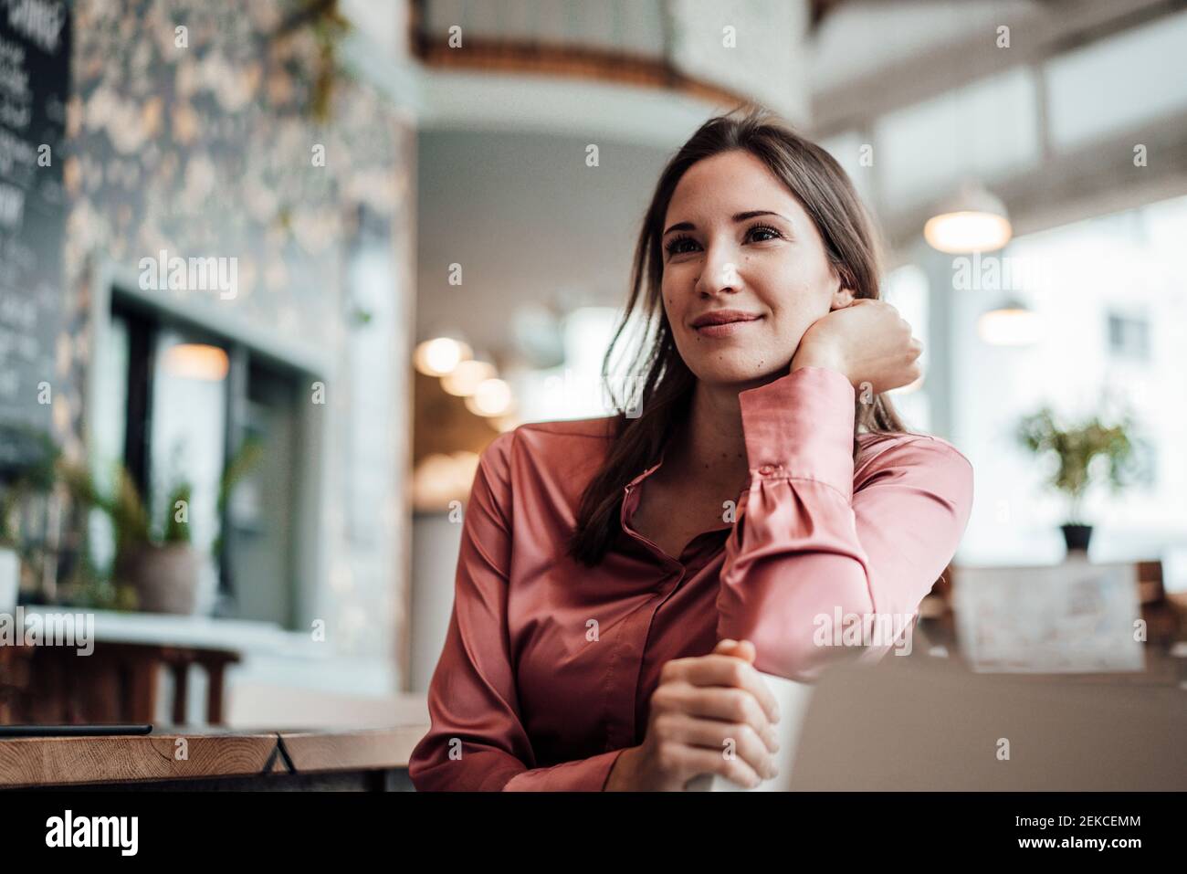 Smiling businesswoman contemplating while sitting in cafe Stock Photo ...