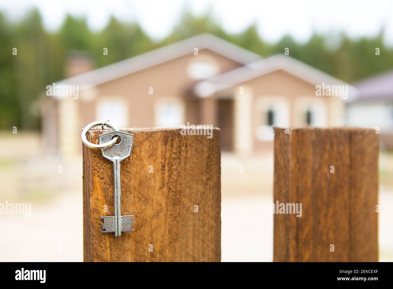The key to the house hangs on a wooden fence against the background of ...