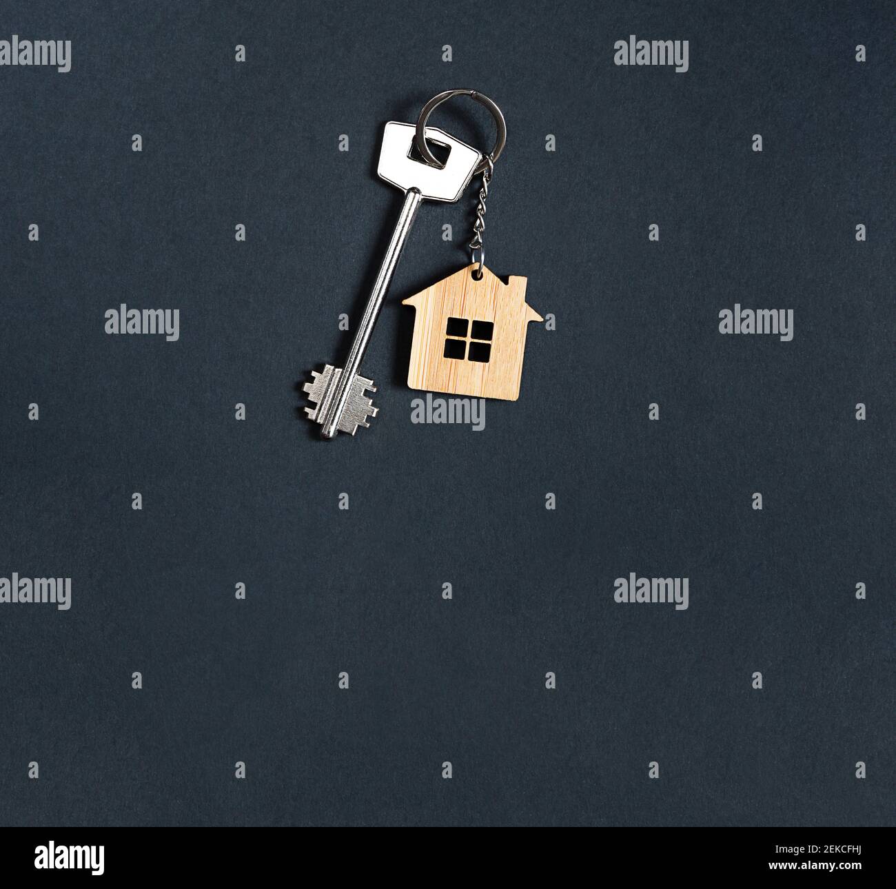 Key chain in the shape of wooden house with key on a black background ...