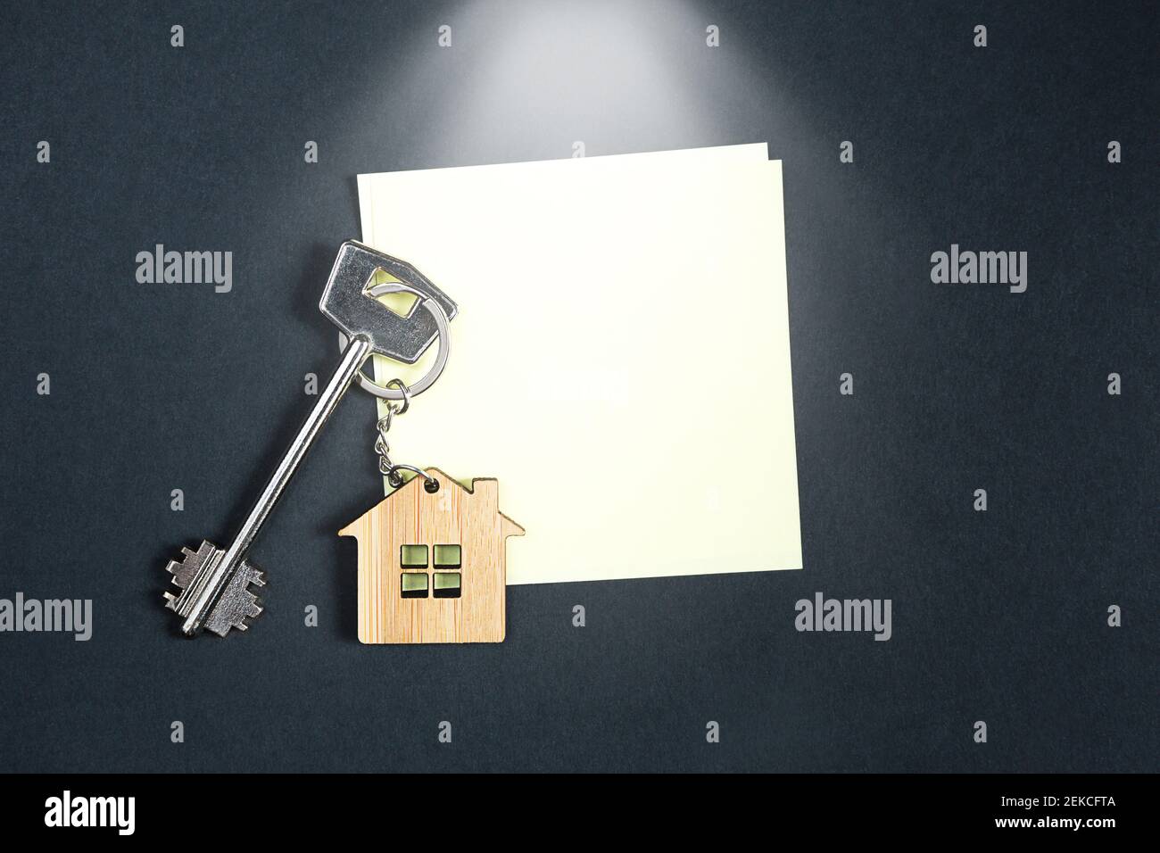 Keychain in the shape of wooden house with key on a black background ...