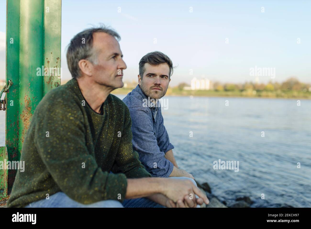 Son looking at thoughtful father by river Stock Photo - Alamy