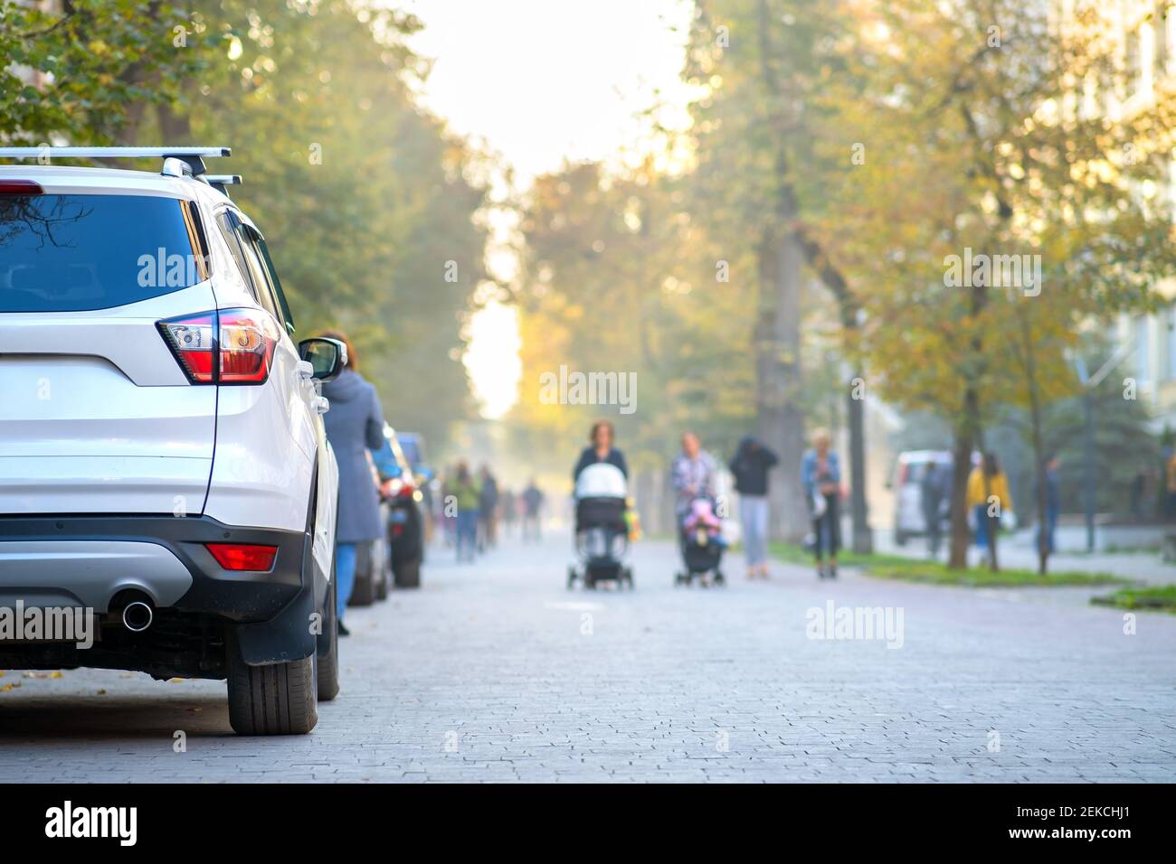 Car parked on a city street side on bright autumn day with blurred ...