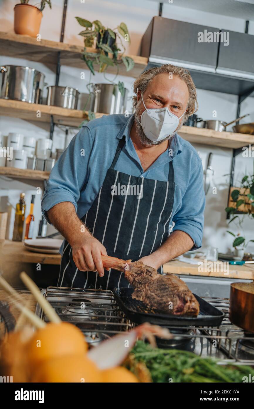 Mature expertise wearing face mask grilling tomahawk steak in frying ...