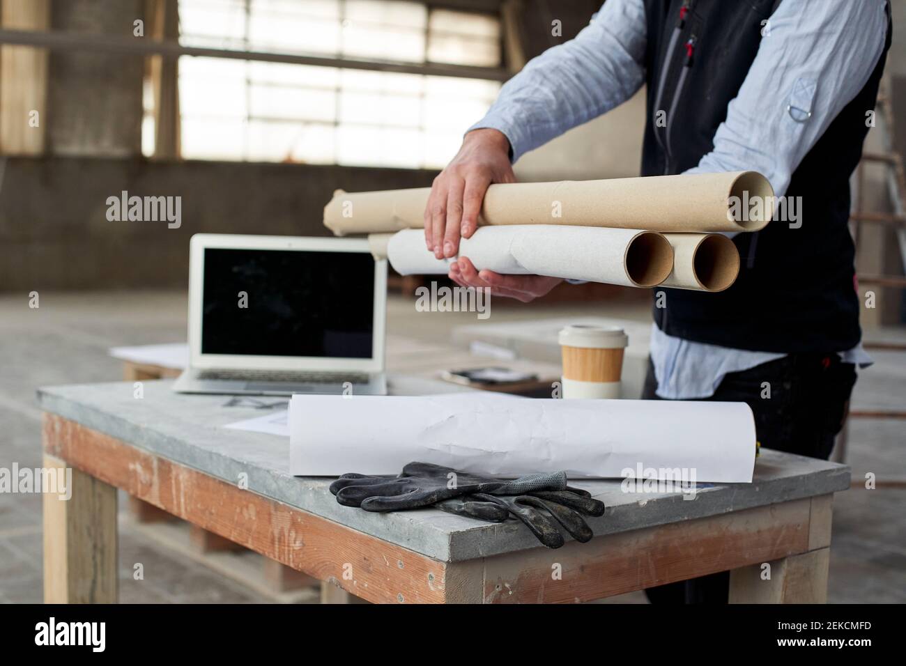 Male architect holding papers while standing at table in building Stock ...