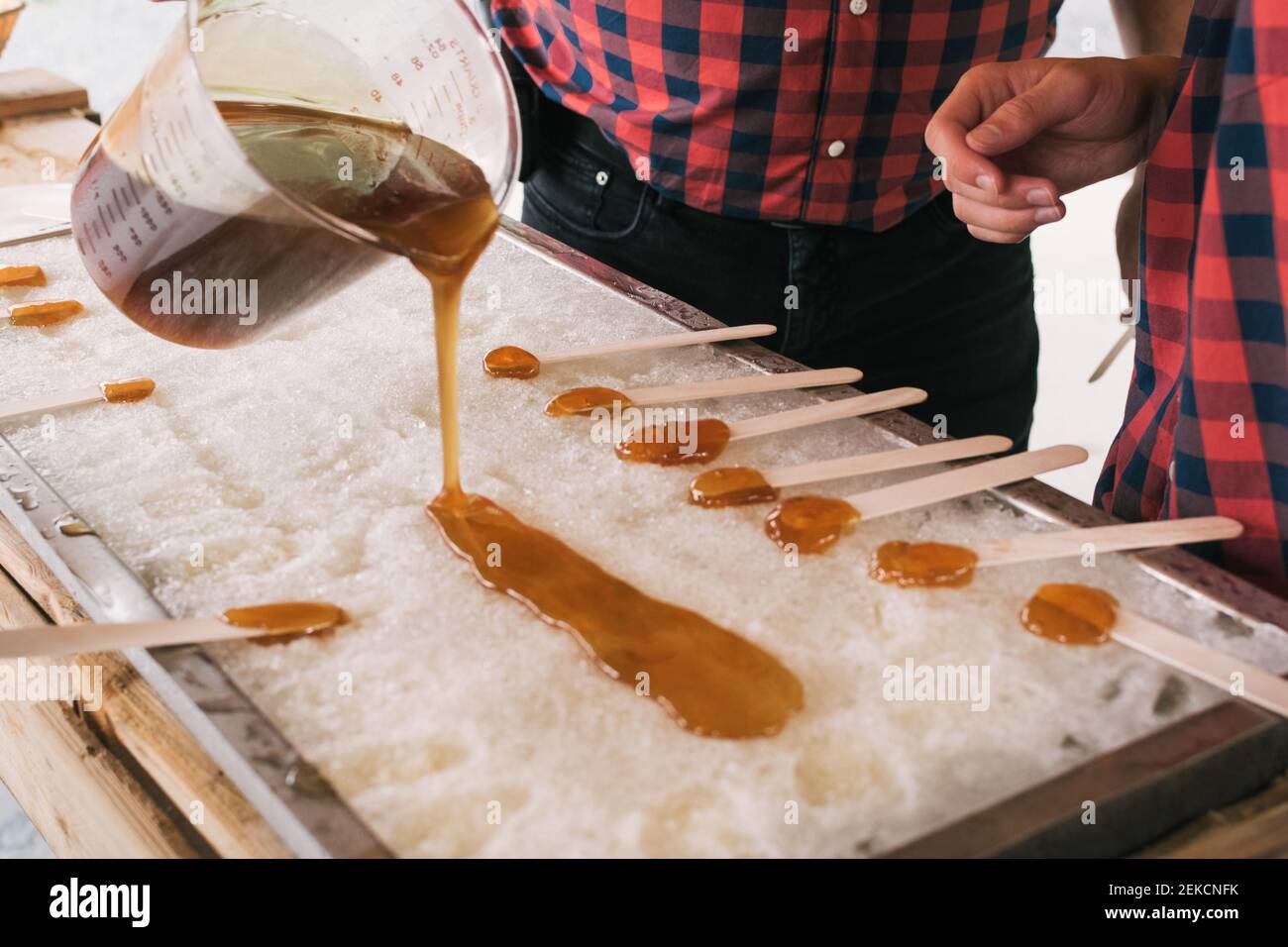 Two man pouring maple syrup on ice Stock Photo - Alamy
