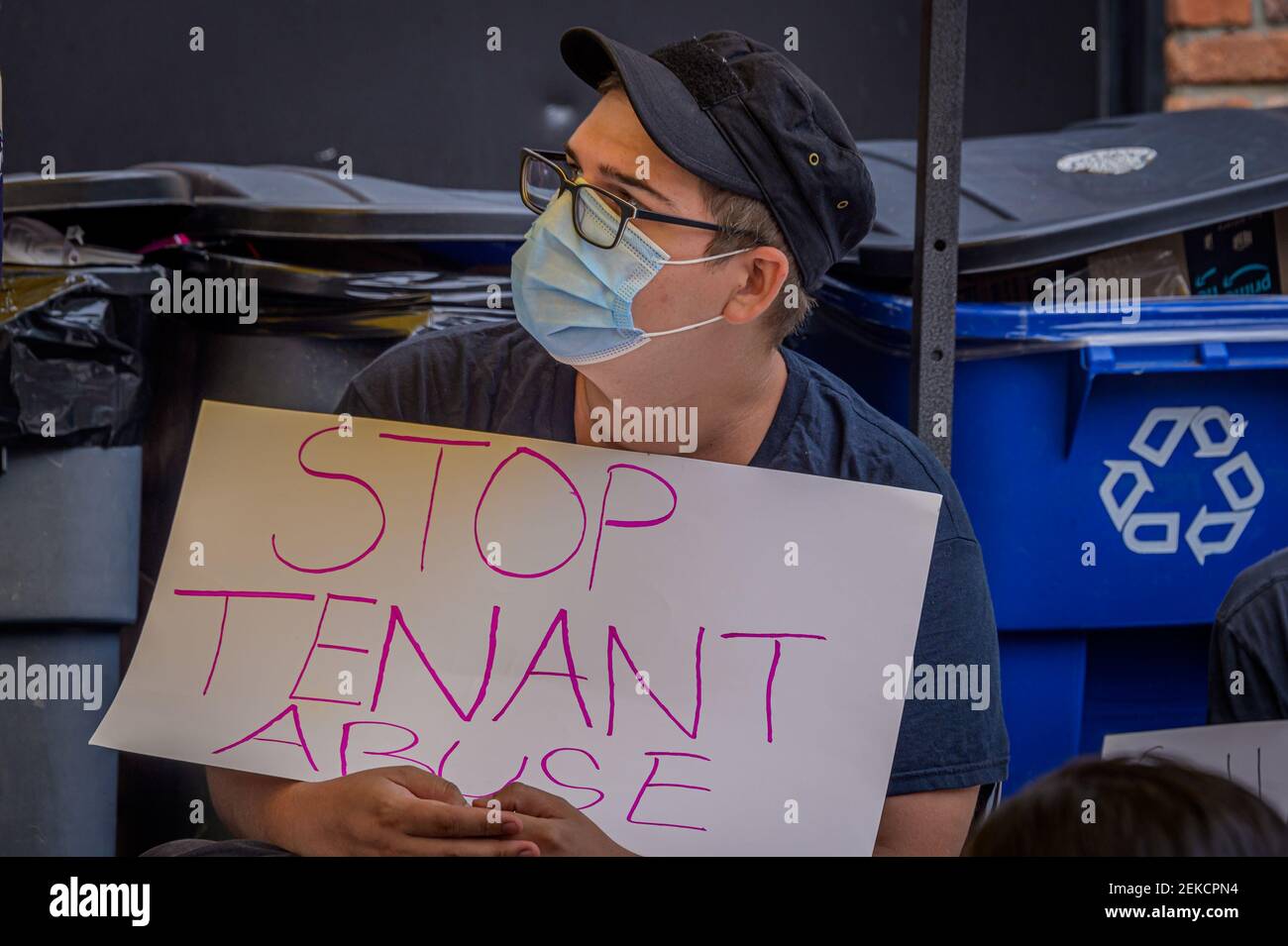 Participant holding a Stop Tenant Abuse sign at the gathering. A crowd ...