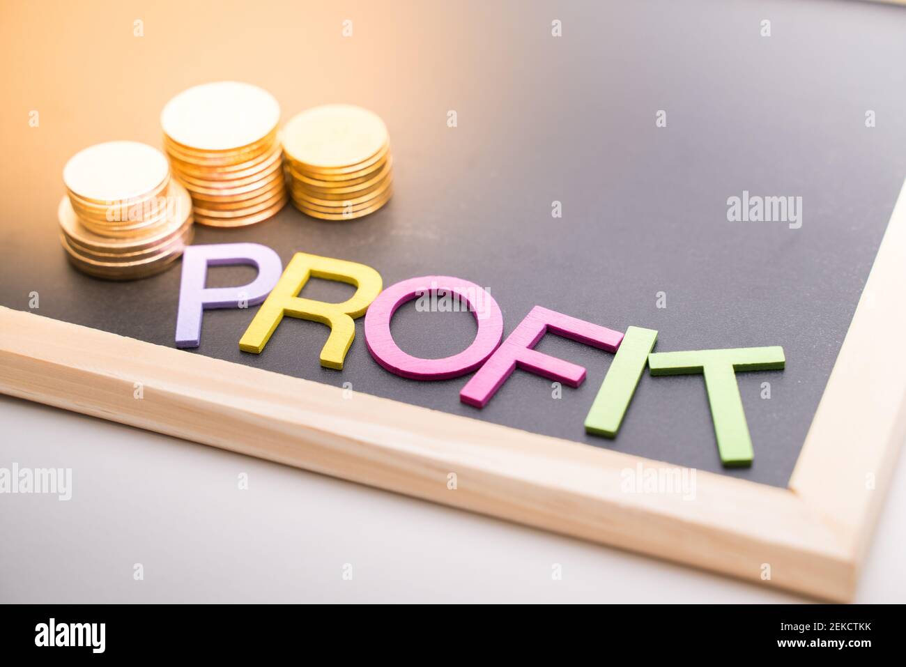 Profit text on blackboard with coin and light Stock Photo - Alamy