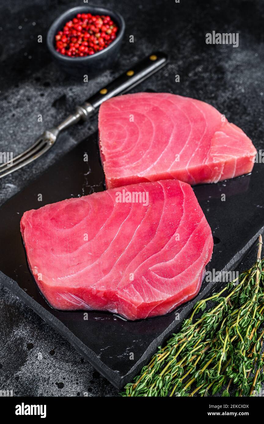 Raw tuna steak on a marble cutting Board . Black background. Top view ...