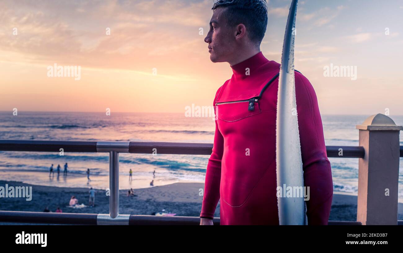 Young surf athlete look at the ocean waves standing with his surf table ...