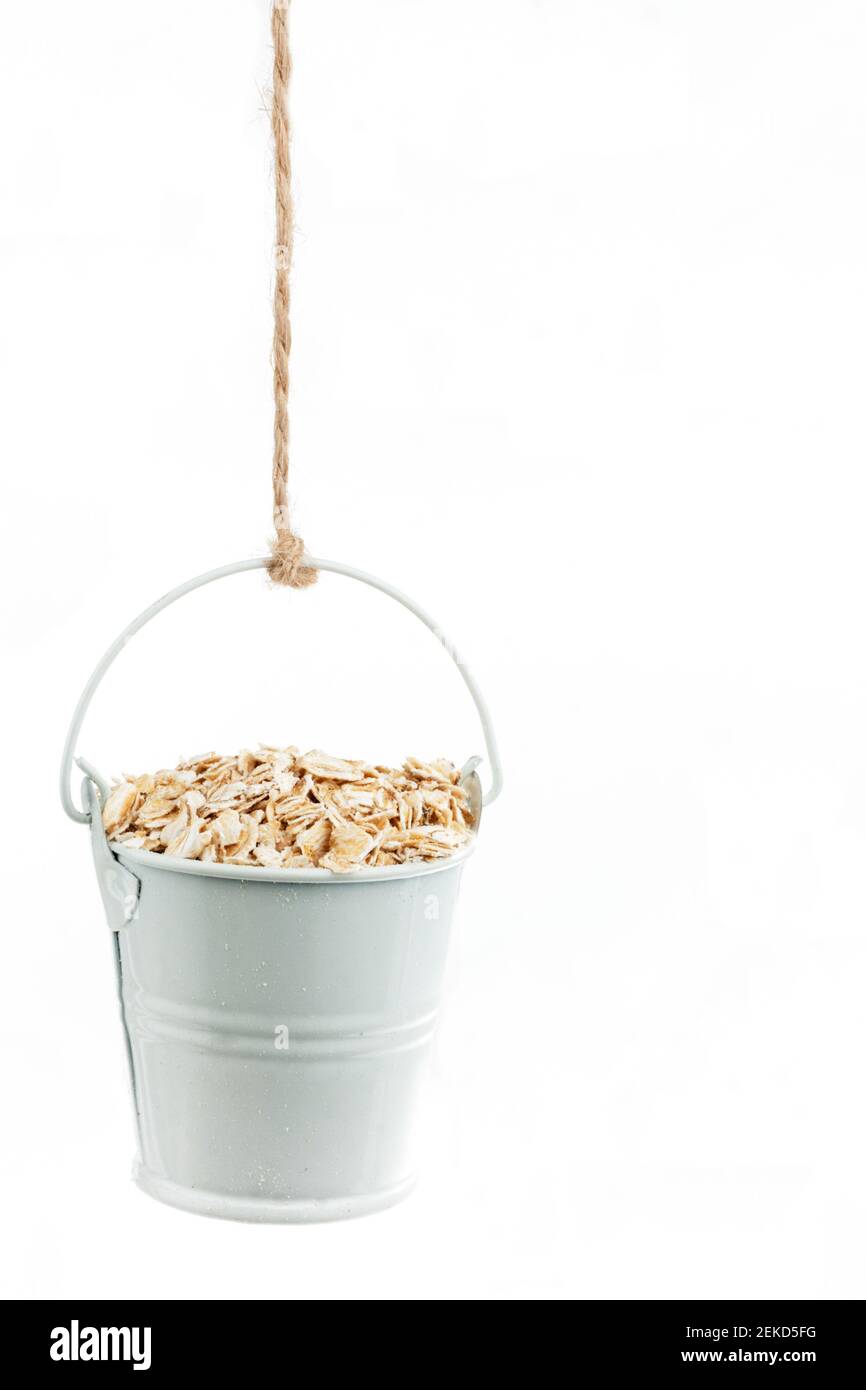 A full bucket of oat flakes hanging from a rope. White background Stock ...