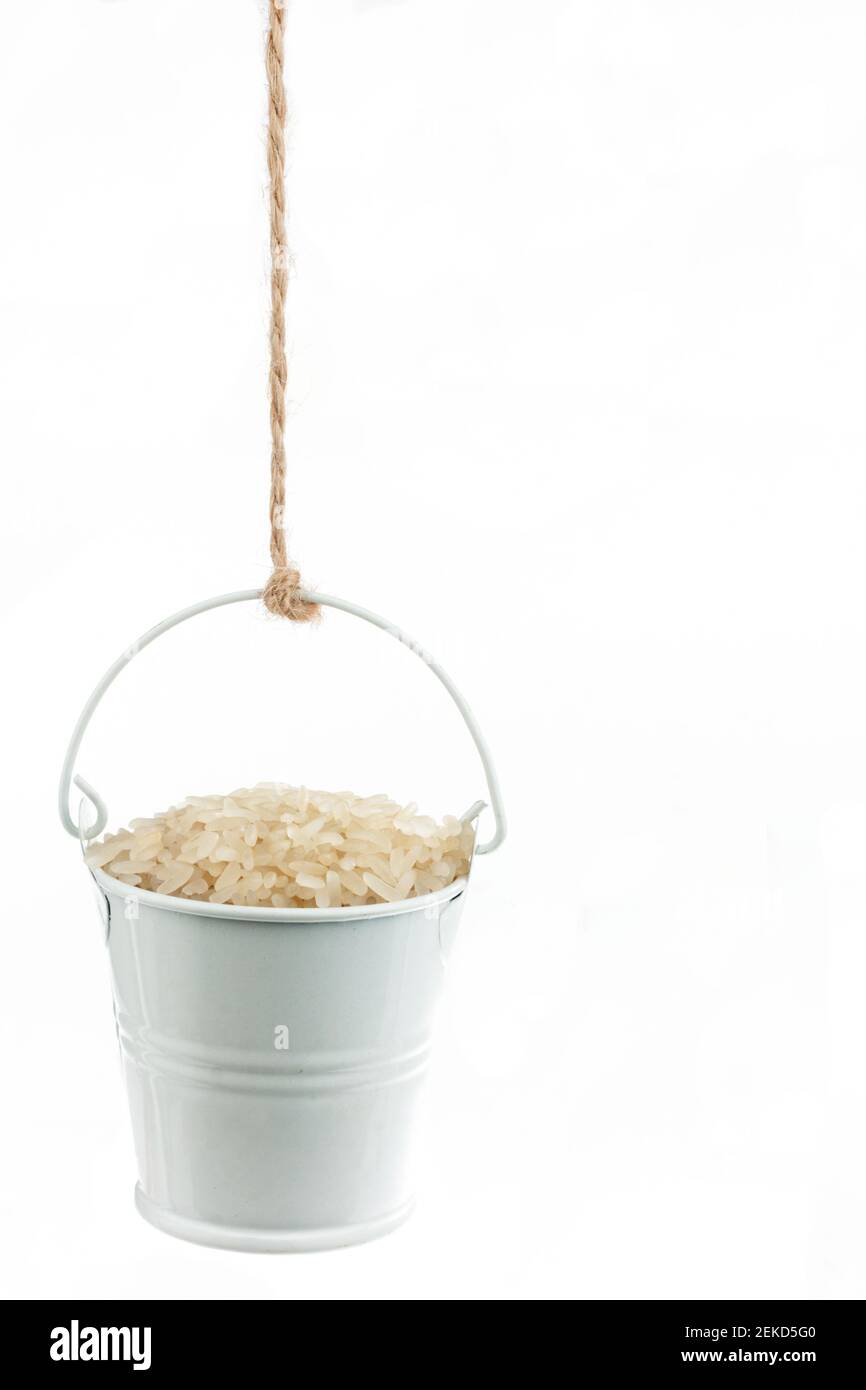 A full bucket of rice grains hanging from a rope. White background ...