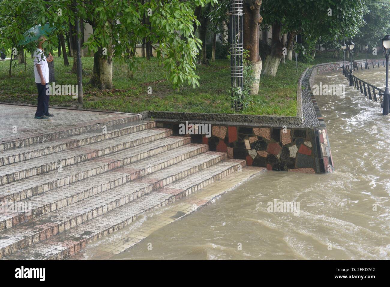 A riverside walking path is flooded by rising water caused by heavy ...