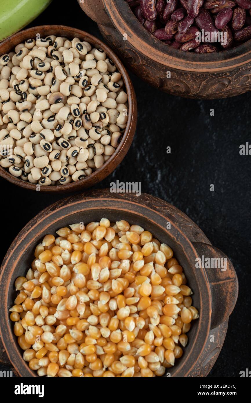 Different kinds of bean seeds, lentil, peas in dishes on a dark ...