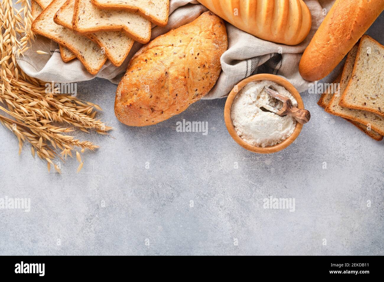 Various crispy breads and buns, wheat flour and ears on light gray ...