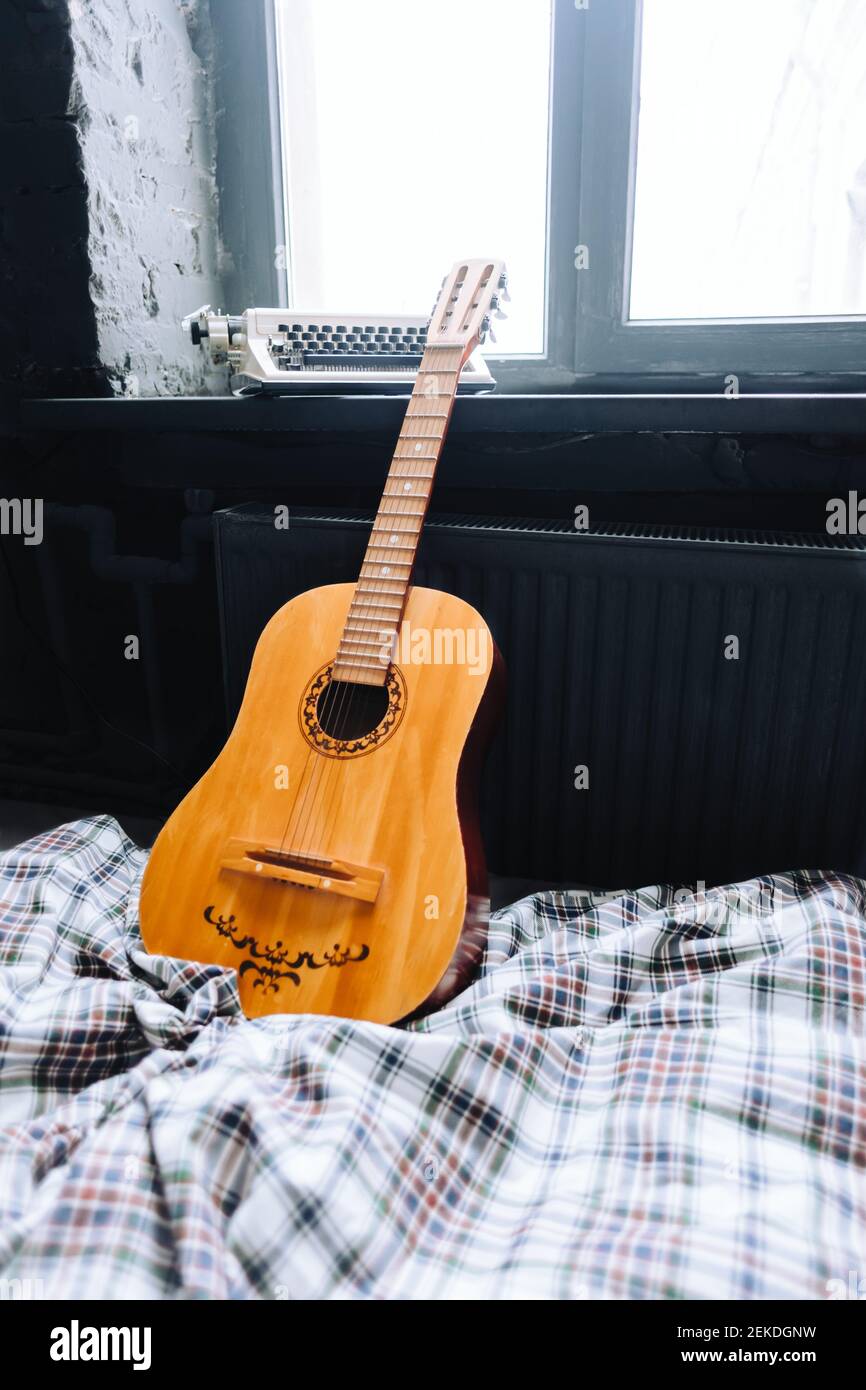 Wooden acoustic guitar on the bed near window Stock Photo - Alamy
