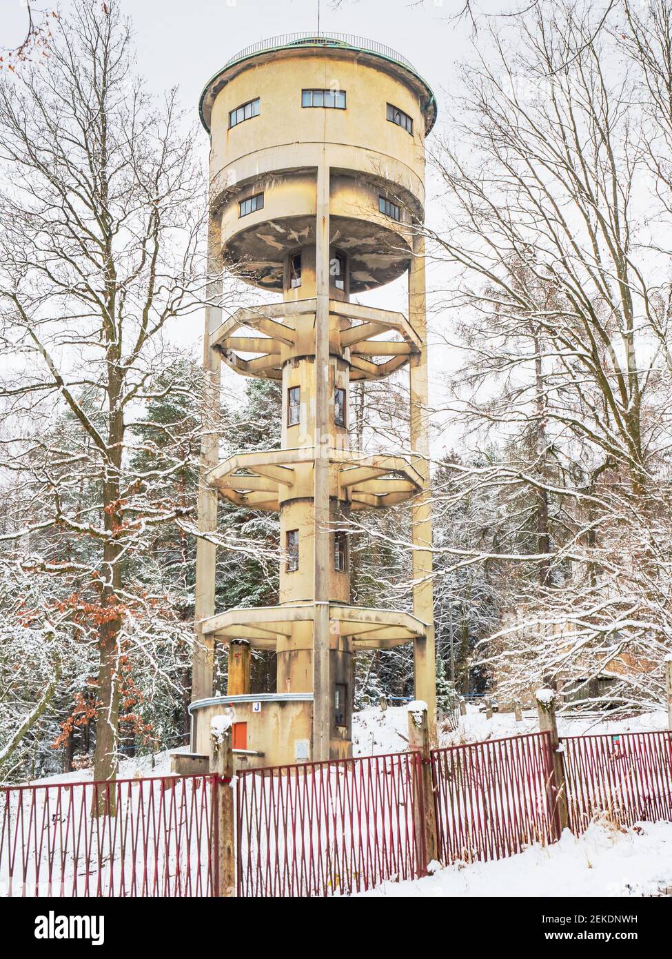 Water tower in a snowy forest park at field against a cloudy sky ...