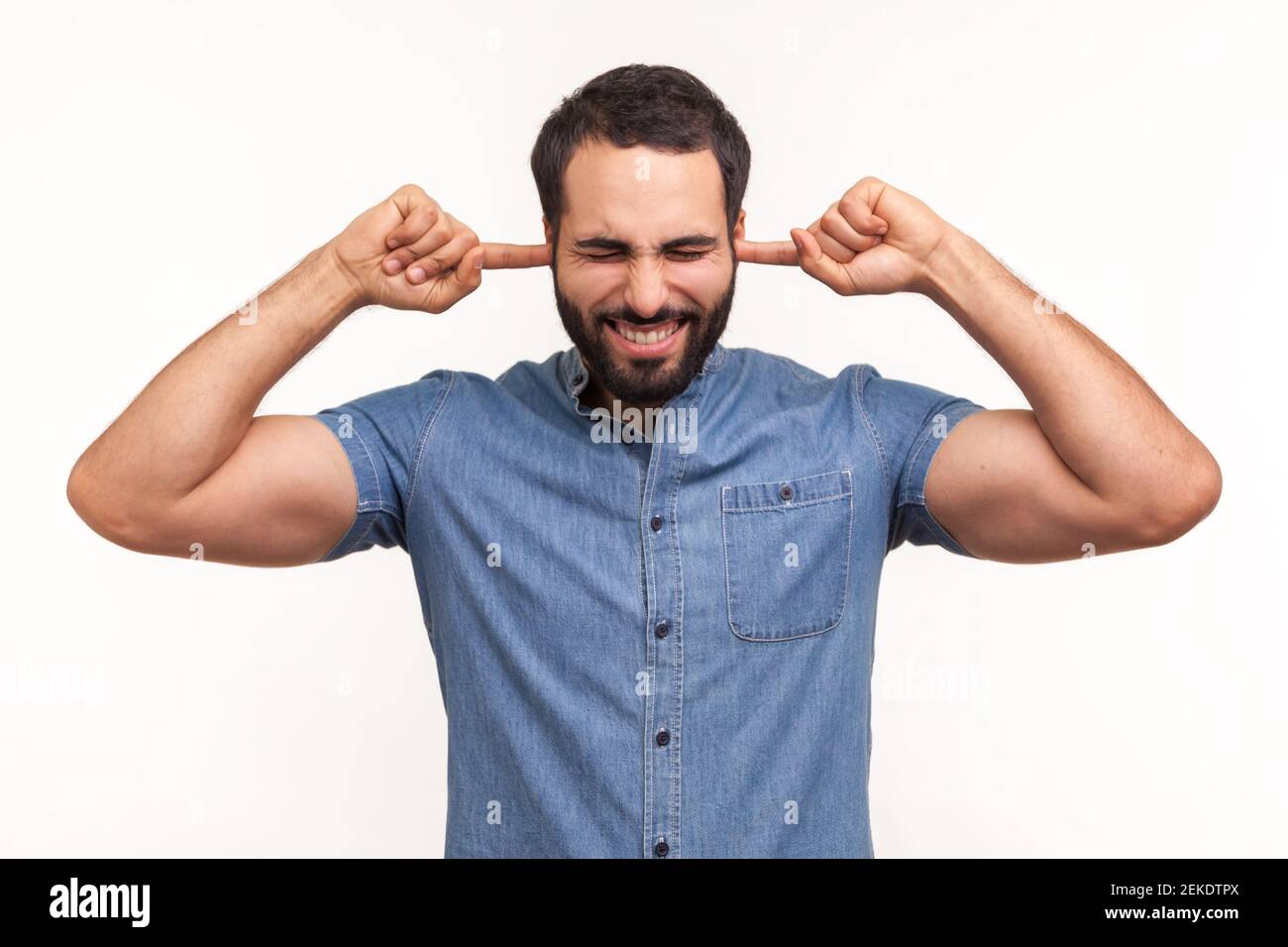 Nervous irritated man with beard covering ears with fingers tightly ...