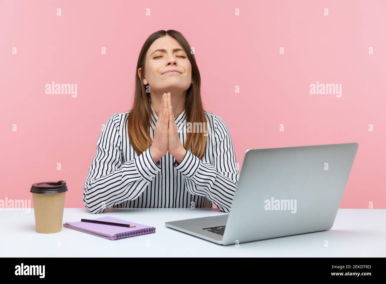 Hopeful brunette woman pressing hands and praying heartily, keeping ...