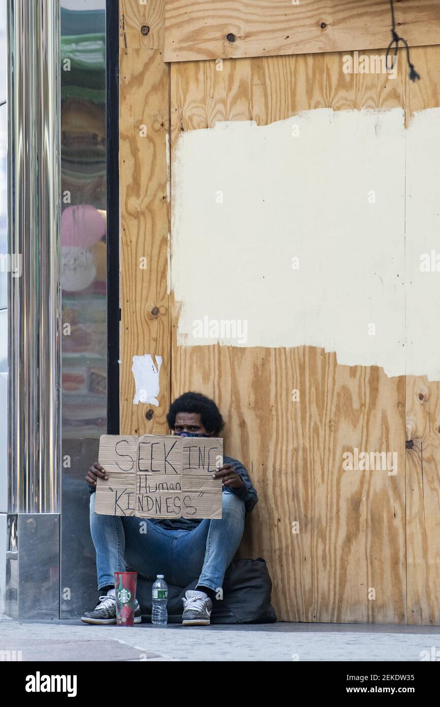 August 17, 2020: A homeless man sits in front of the boarded up ...