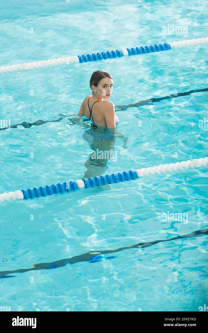 Back view of young woman looking at camera in swimming pool Stock Photo ...