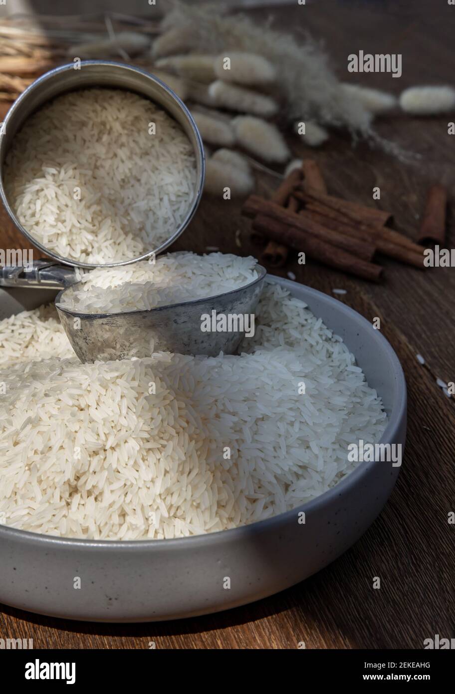 Thai jasmine rice pouring from old steel can with steel dipper on bowl ...