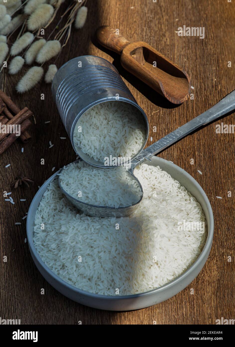 Thai jasmine rice pouring from old steel can with steel dipper on bowl ...