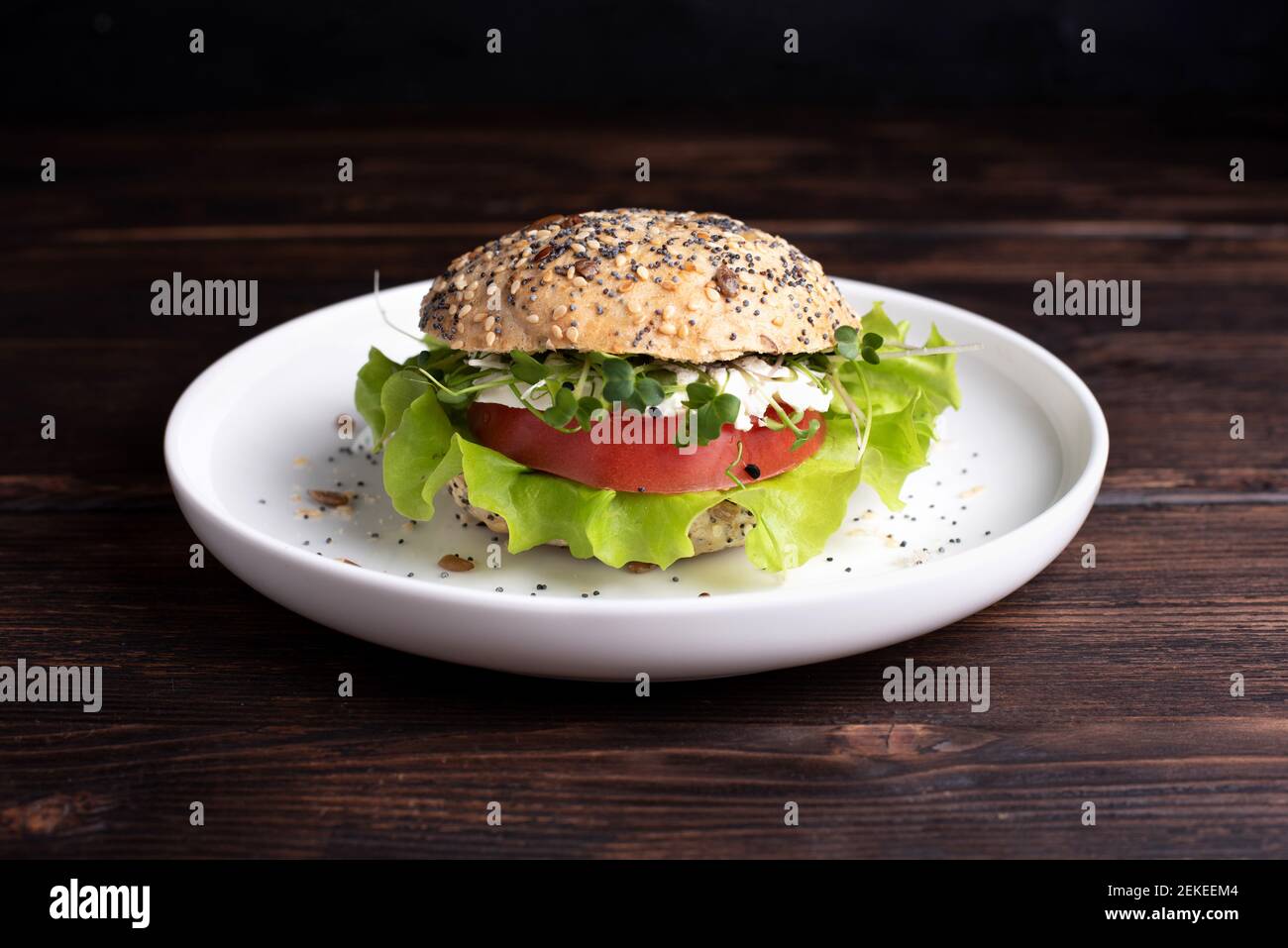 Vegetarian burger with tomato, cheese and micro grins on a white plate ...