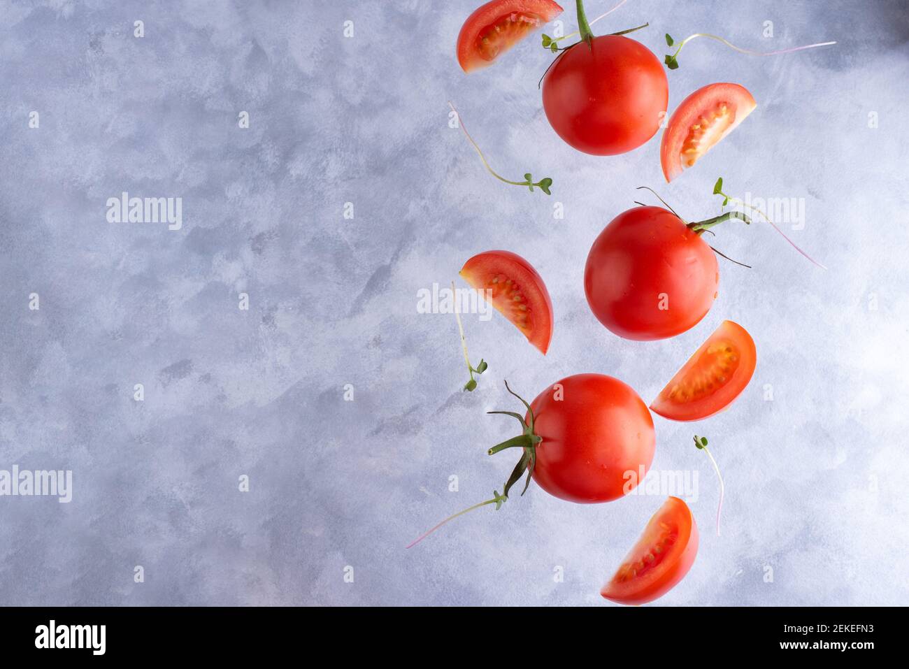 Three fresh red tomatoes with micro grins on a gray background, top ...