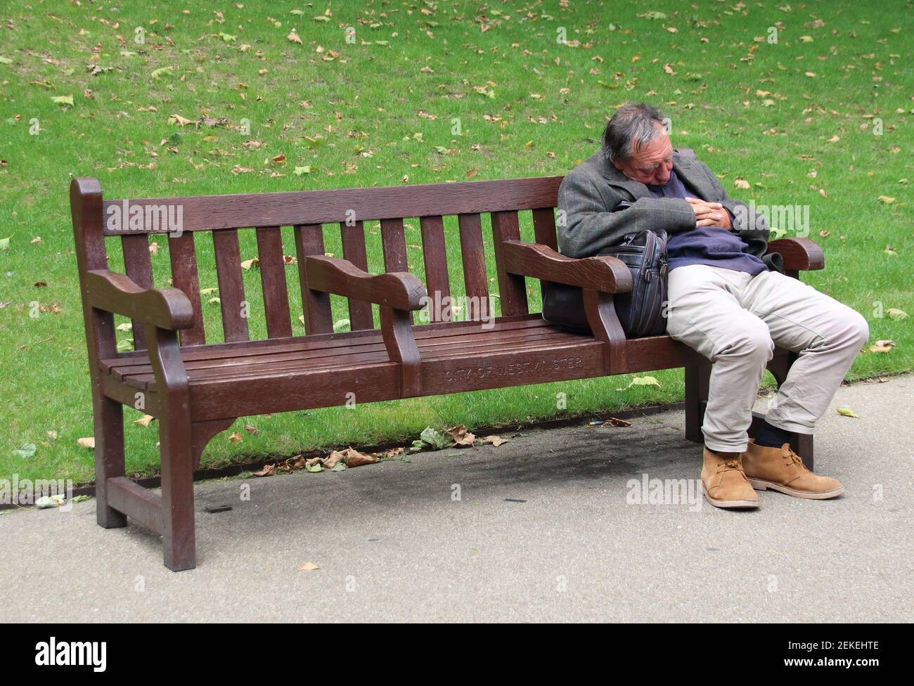 Man slumping asleep on a park bench. Following the relaxation of ...