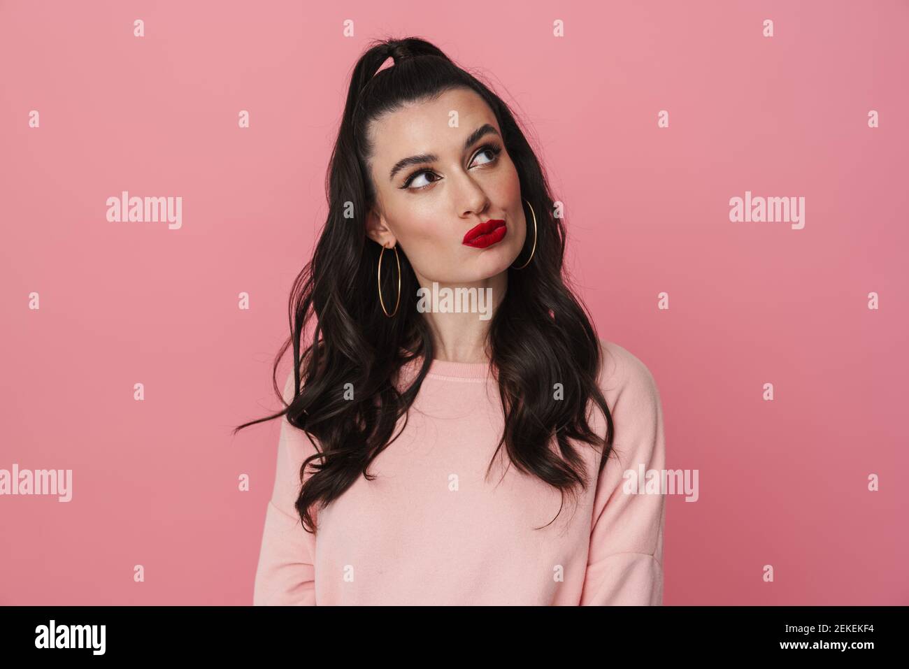 Beautiful pensive young woman in casual wear standing isolated over ...