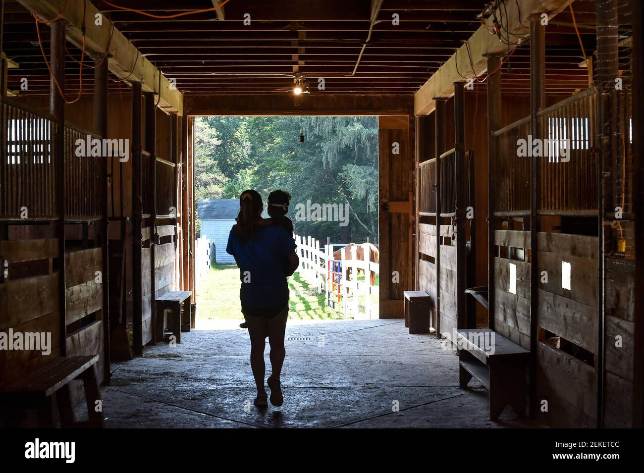 Catherine Davey carries a young camper through the coach barn at ...