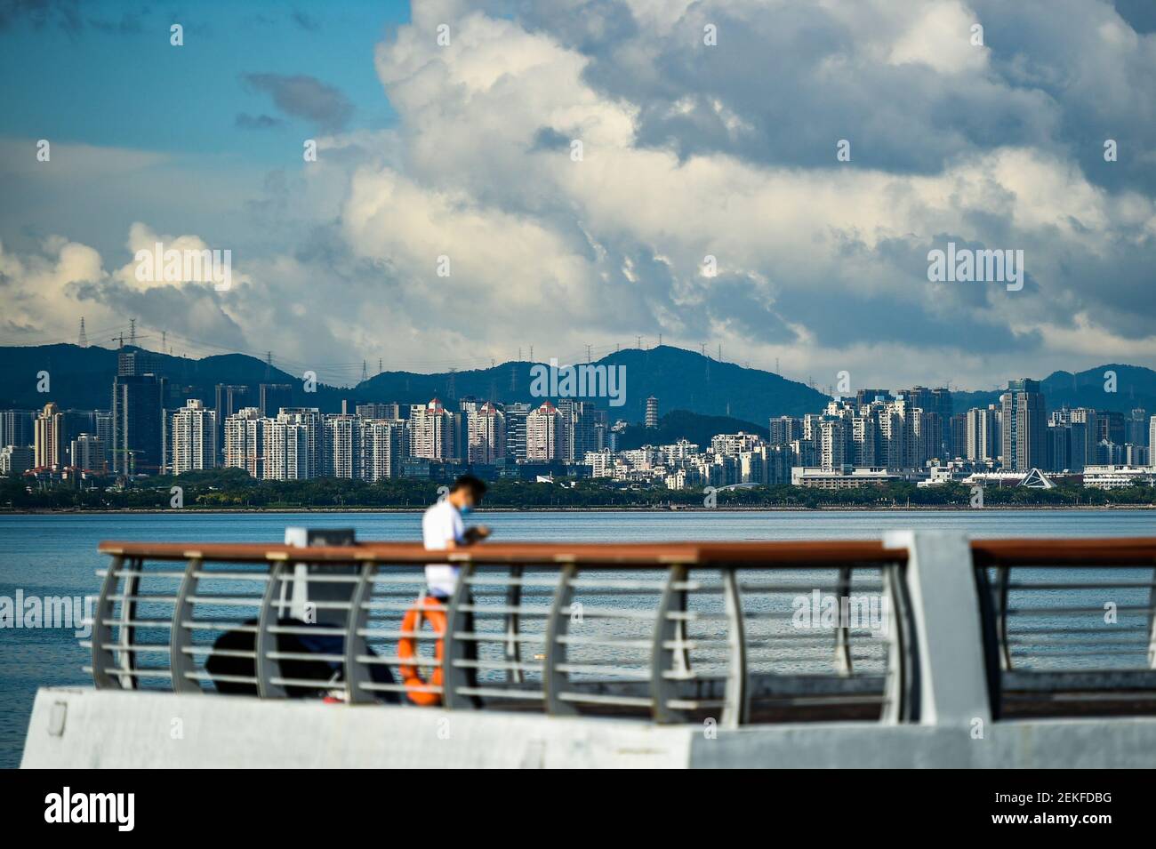 Citizens enjoy cozy life at a waterside platform with skyscrapers ...