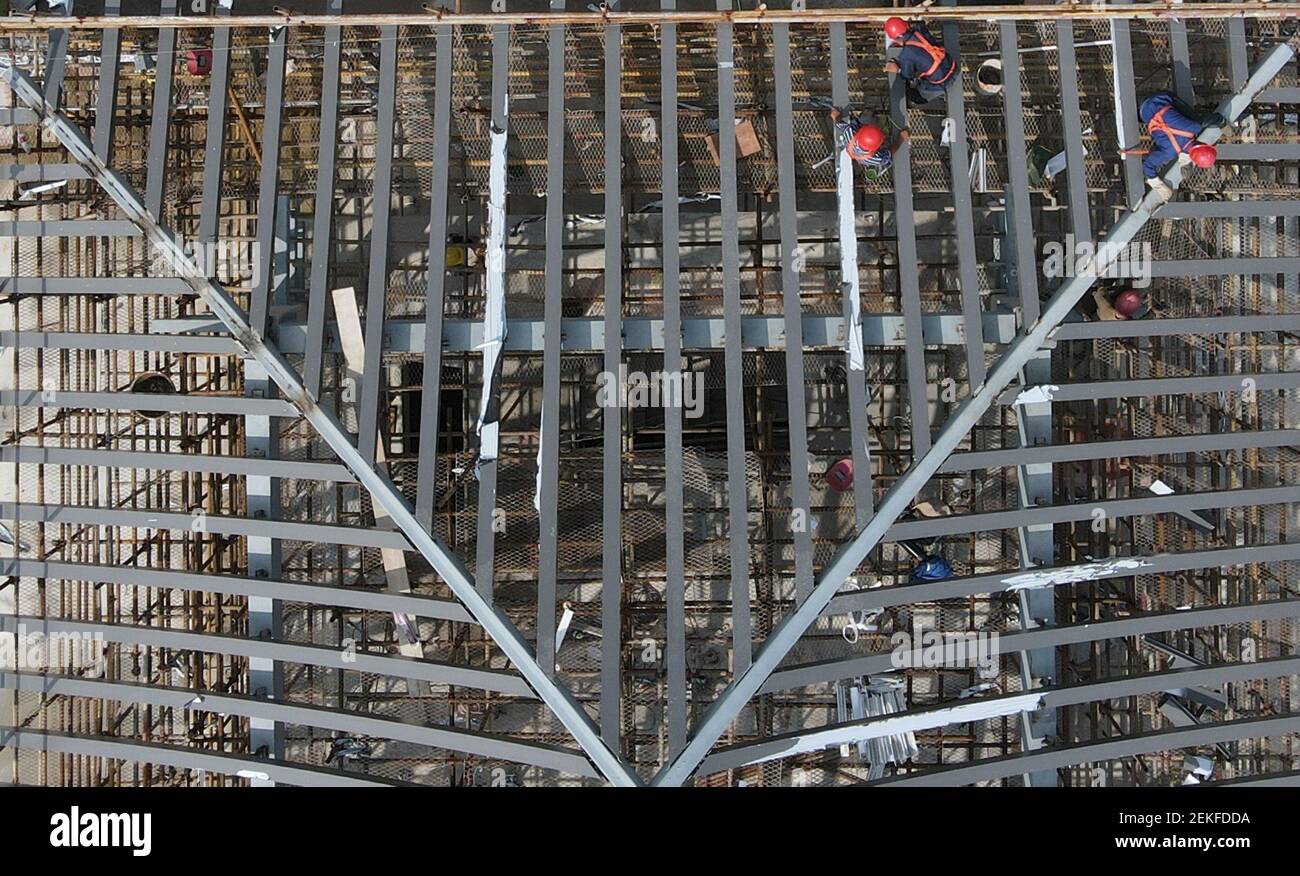 An aerial view of workers, with help of cranes and machines, building ...