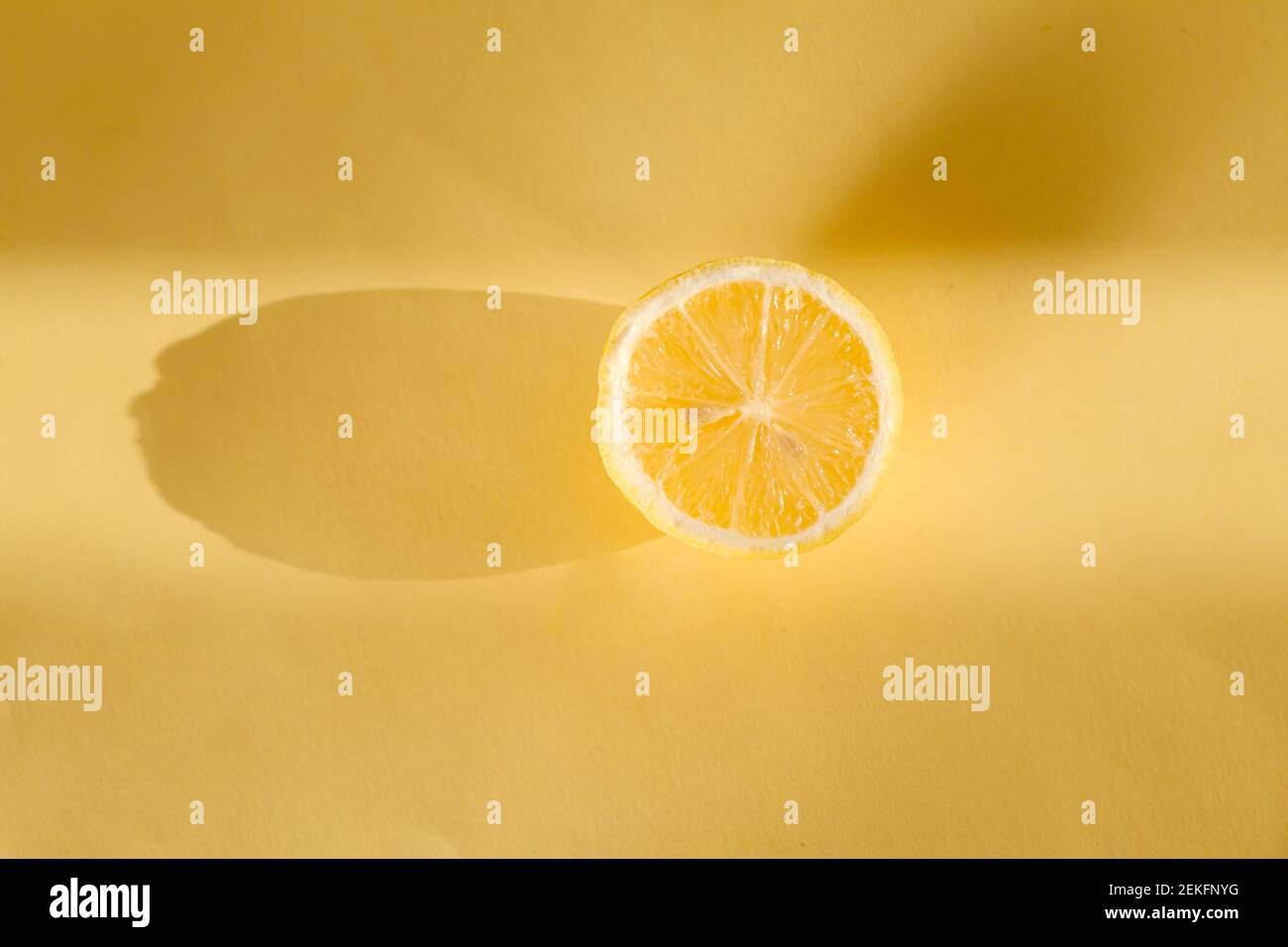 half of lemon top view on yellow background with abstract shadows and ...