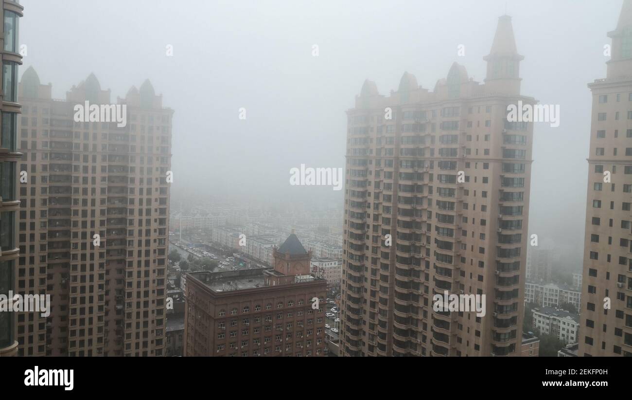 Buildings which can be barely seen, stand in heavy fog caused by ...
