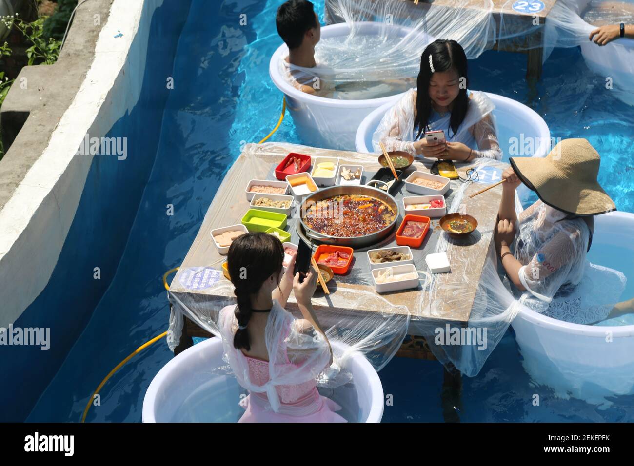 Tourists eat hotpot while sitting in a ice bucket to enjoy spicy ...