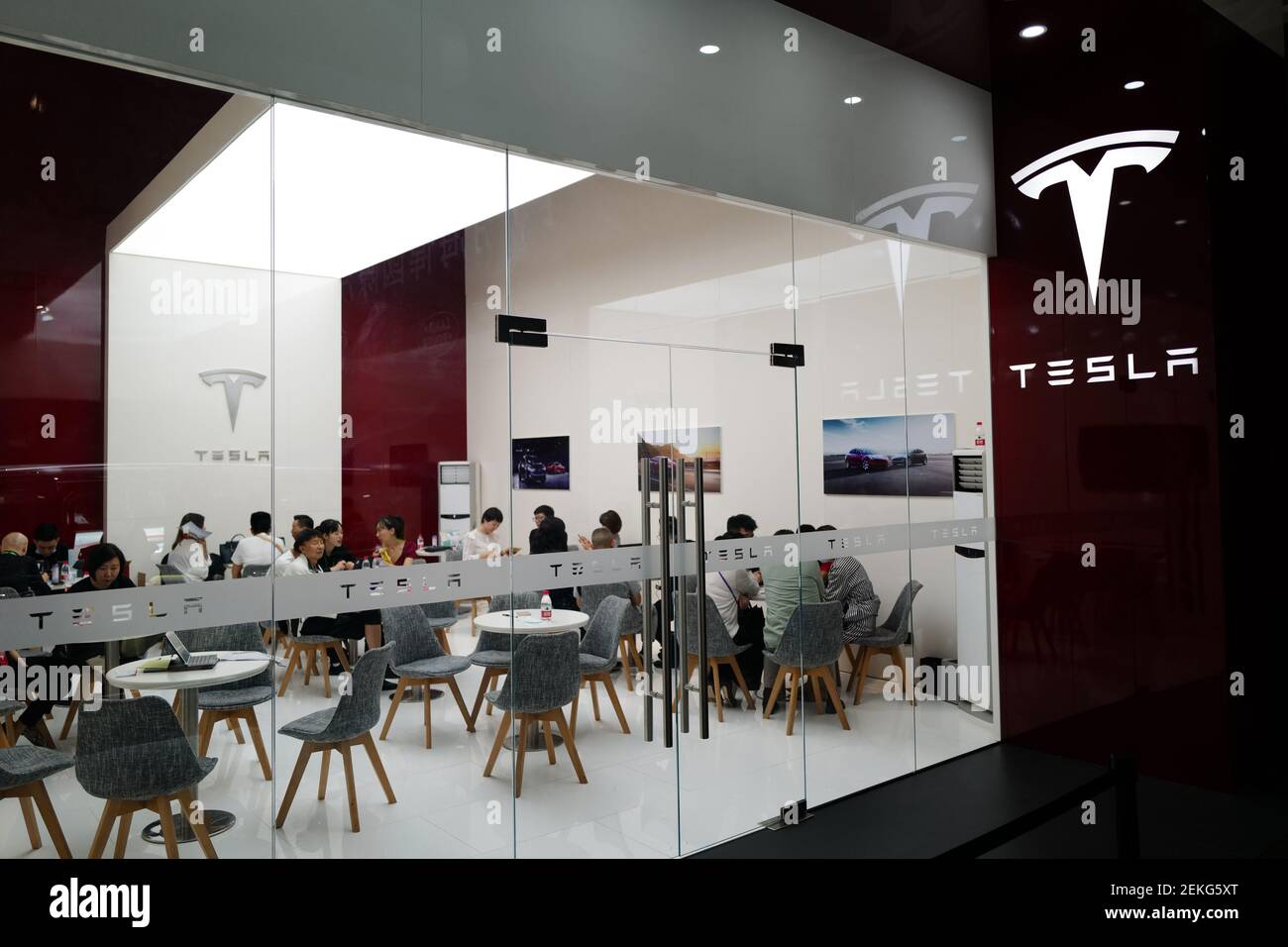 Visitors flock to the booth of Tesla, an American electric vehicle and ...