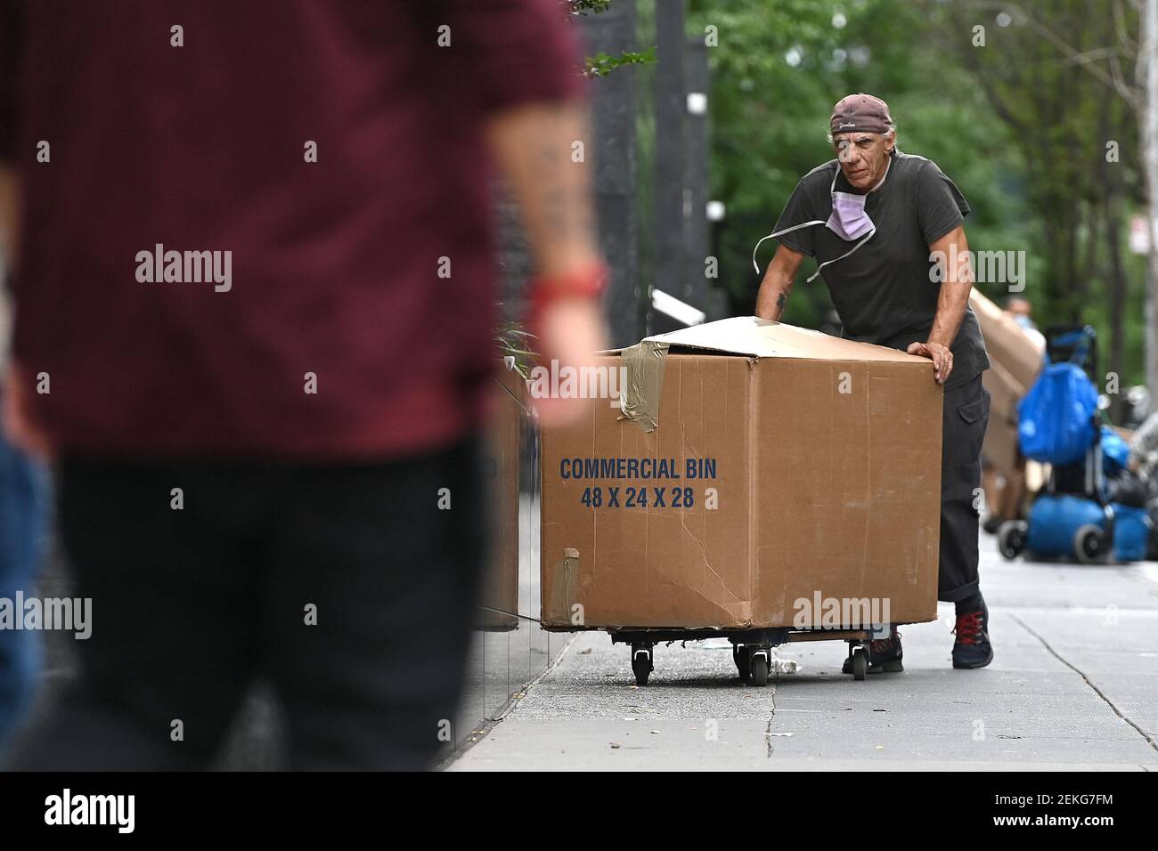 A mover pushes a large box set down the sidewalk towards a waiting ...