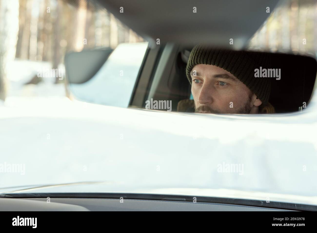 Reflection of face of young active man in winterwear looking through ...