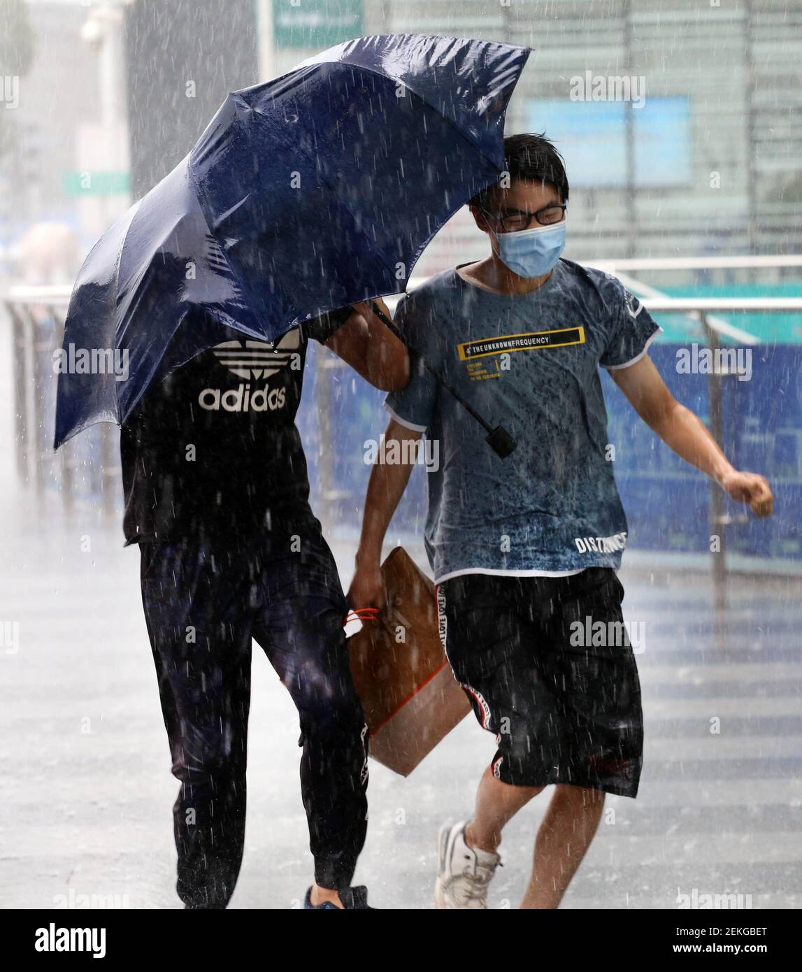 Pedestrians trek with difficulty in the heavy rain while gale blows in ...